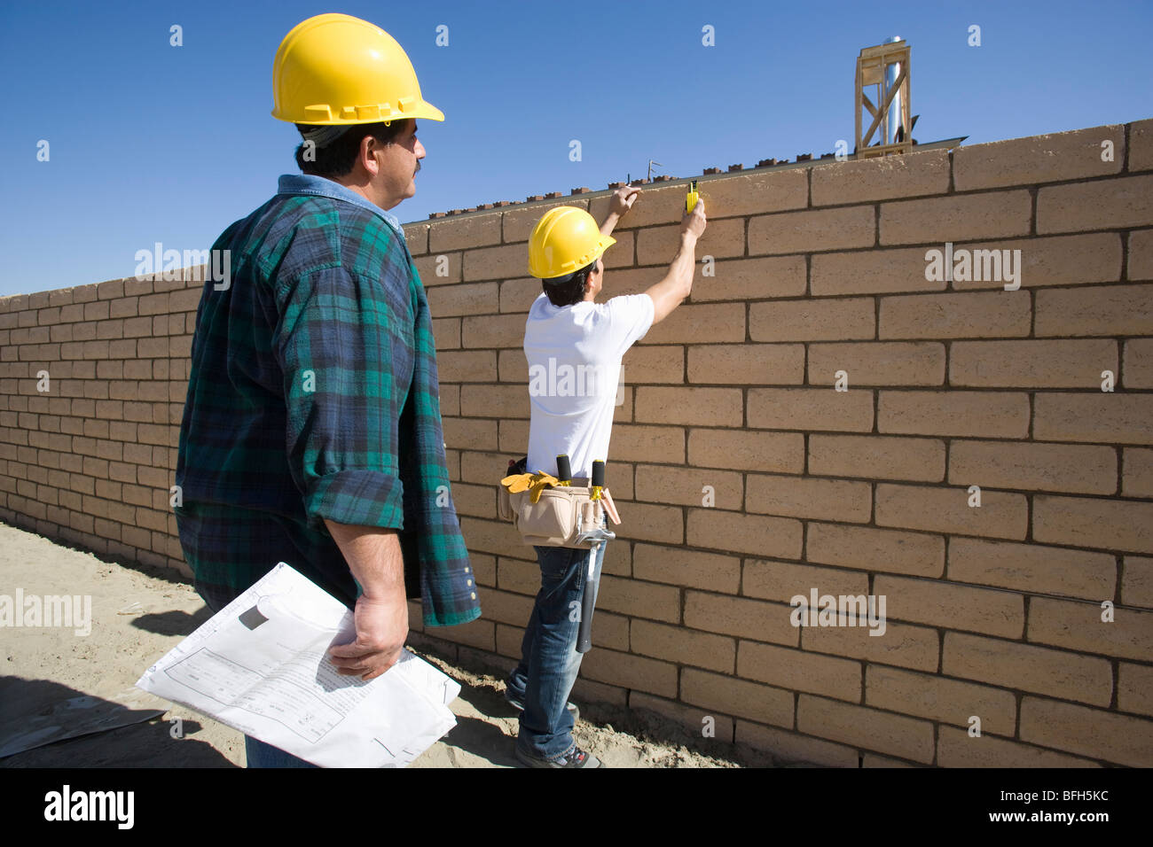 Construction workers standing in front of brick wall Stock Photo - Alamy