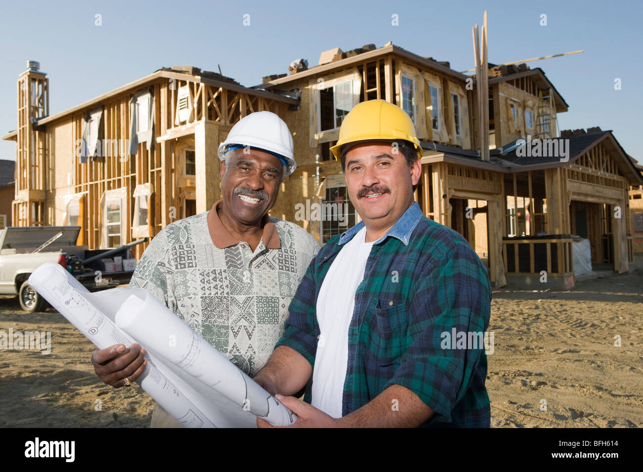 Two men holding blueprints at construction site, portrait Stock Photo ...