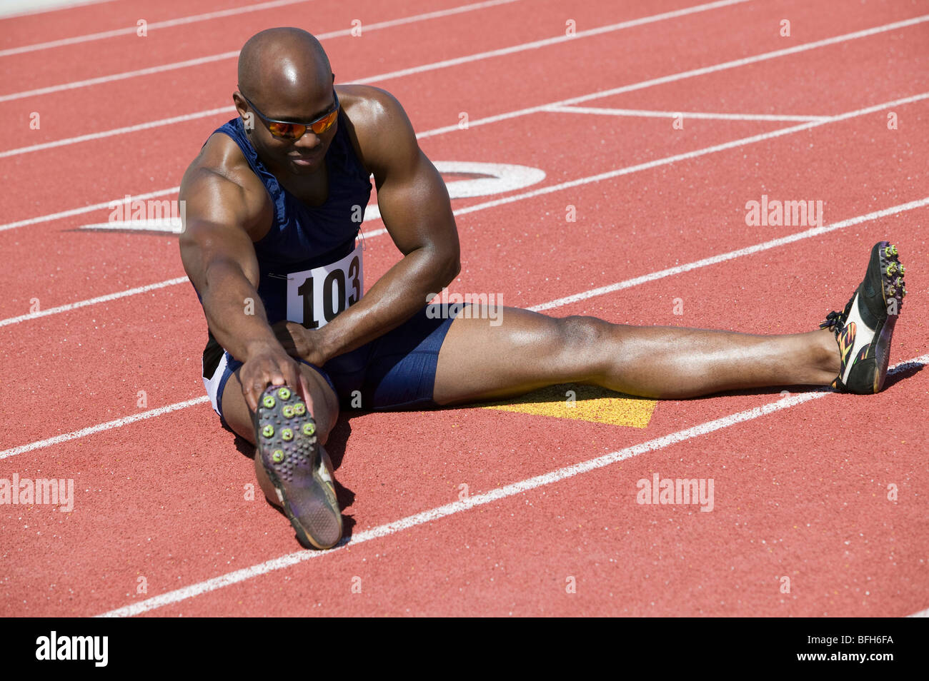 Male sprinter stretching on track Stock Photo - Alamy