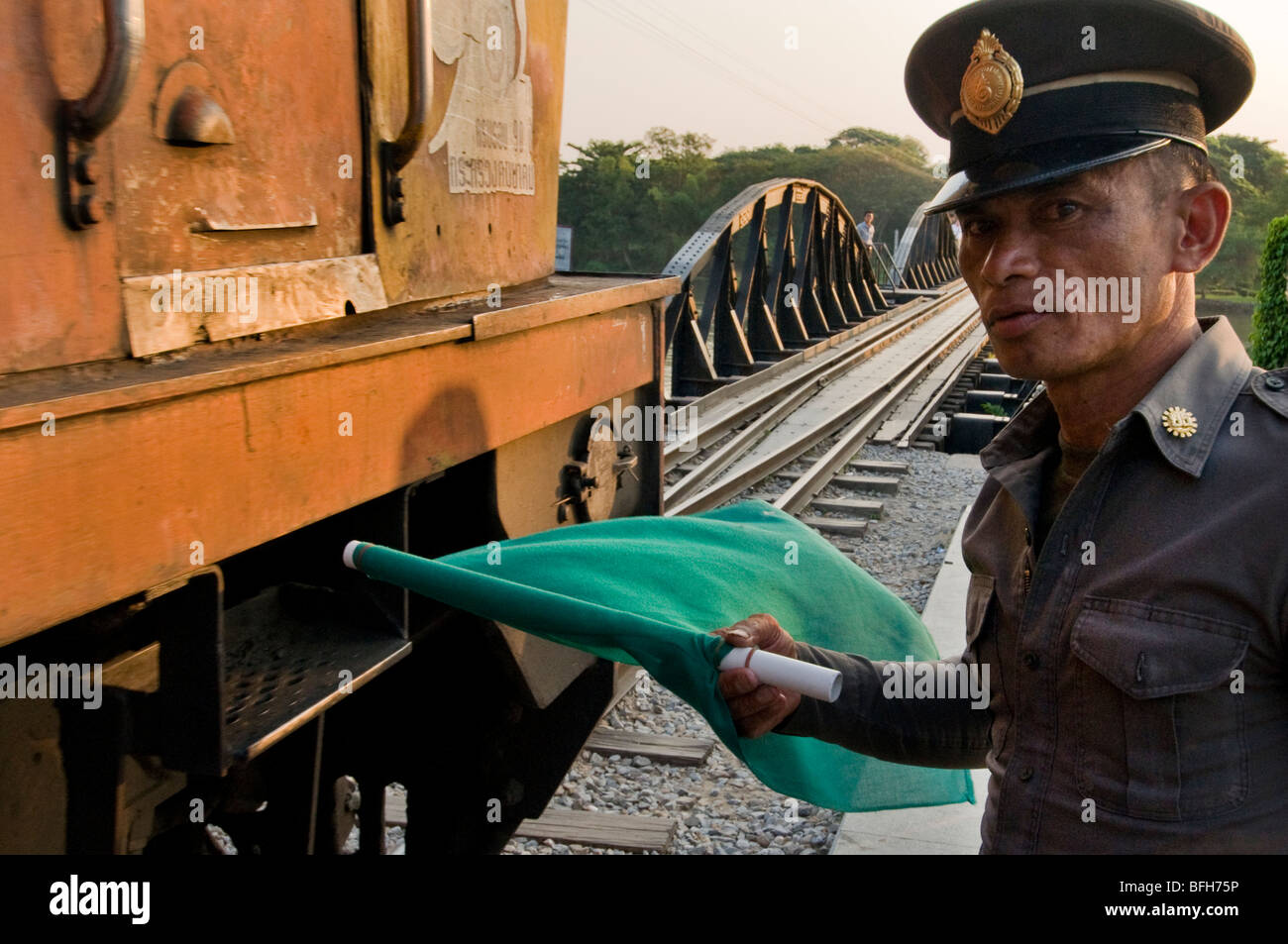 A Thai railways employee giving way to a train over the bridge on the ...