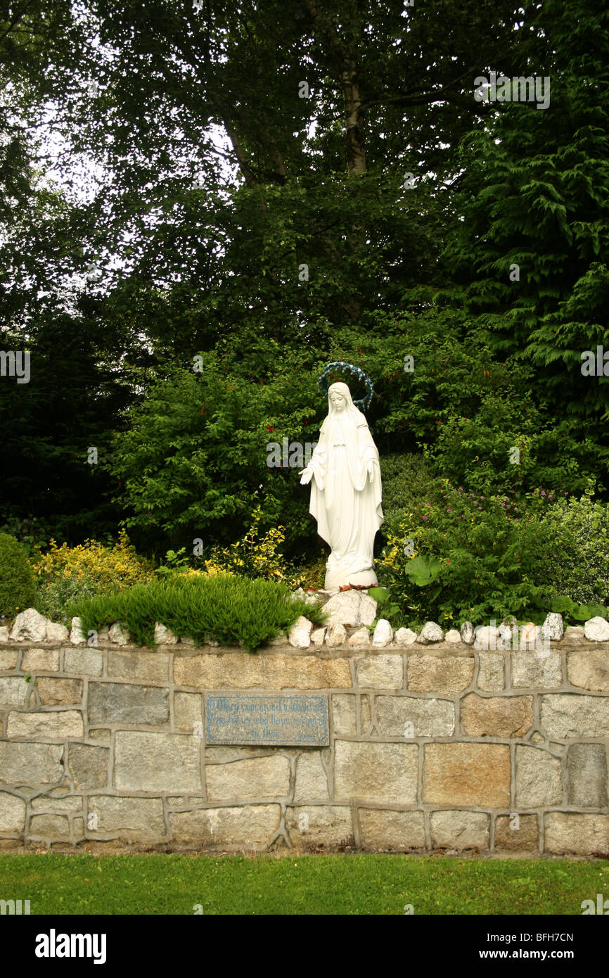 White Statue of Mother Mary on a stone wall in front of Catholic Church ...