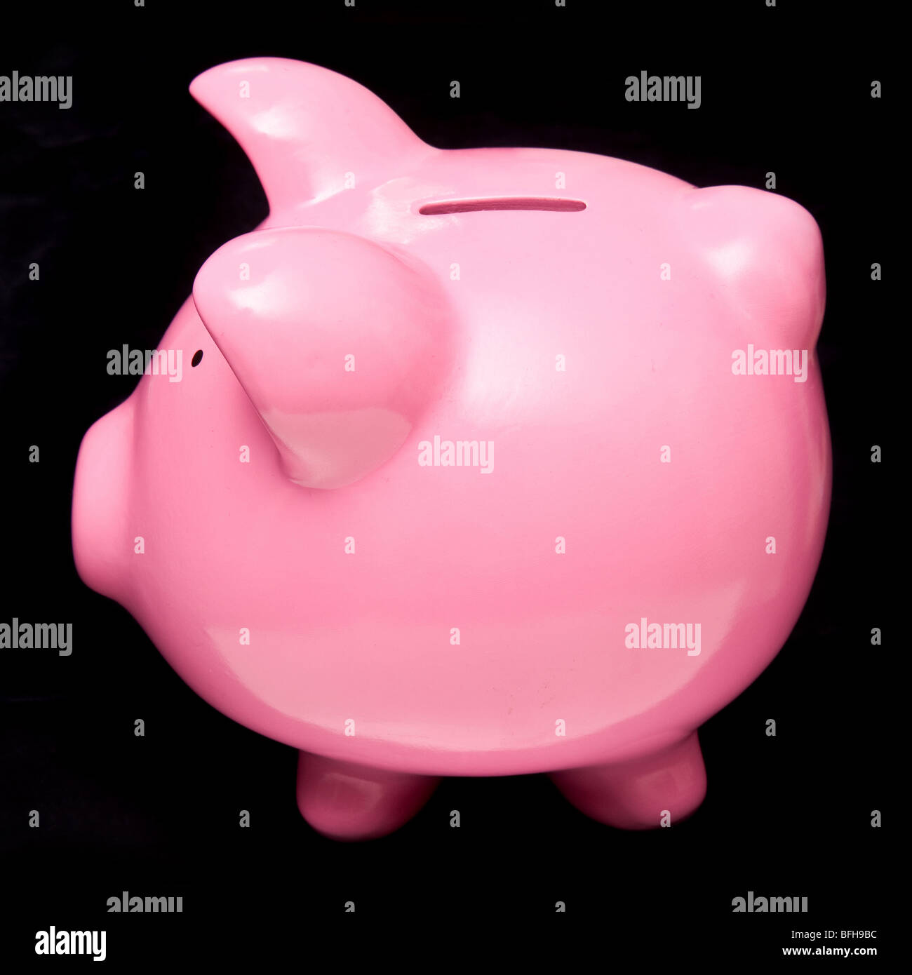 Pink piggy bank style money box isolated on a black studio background ...