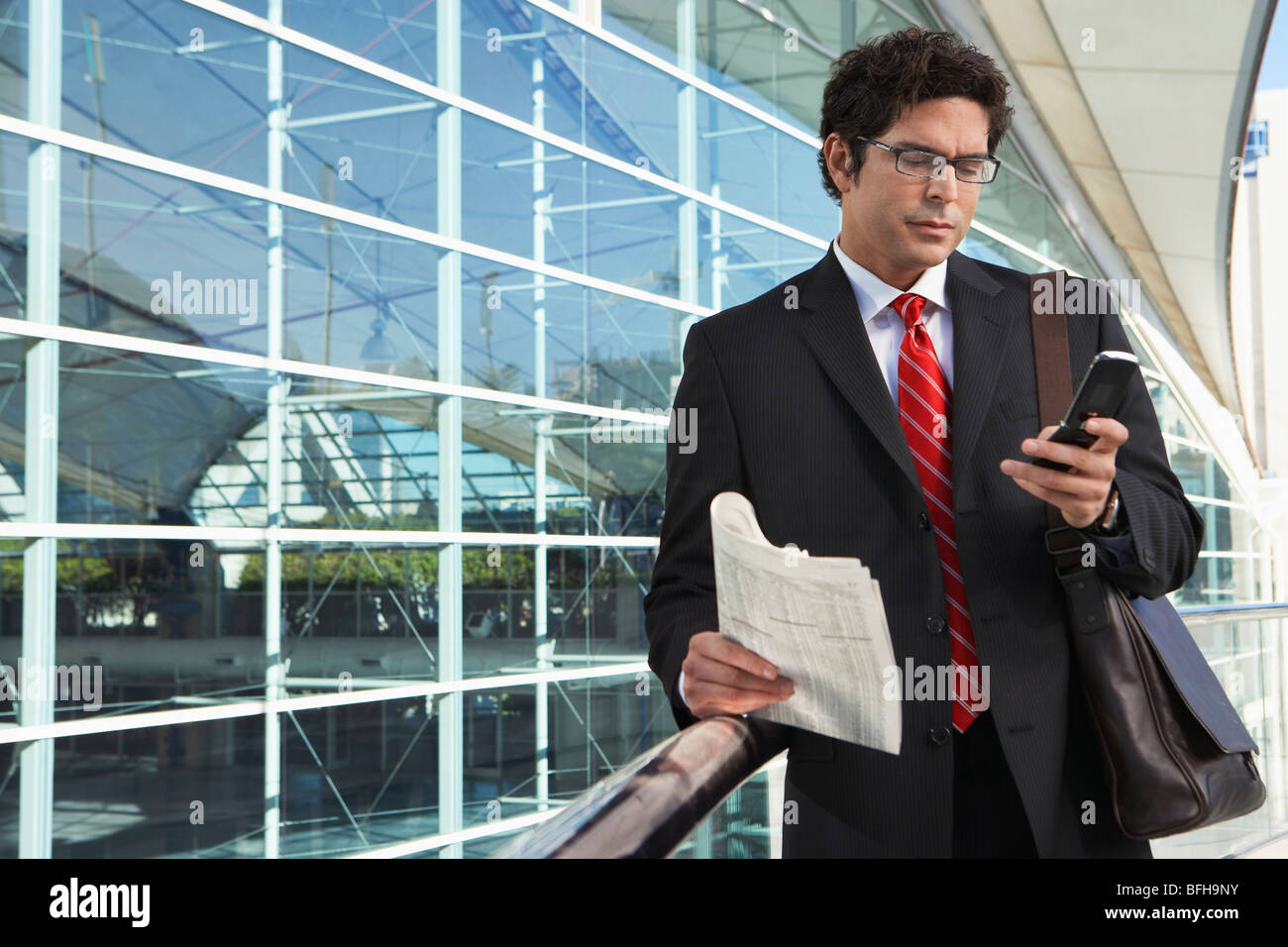 Businessman using mobile phone outside office building Stock Photo - Alamy