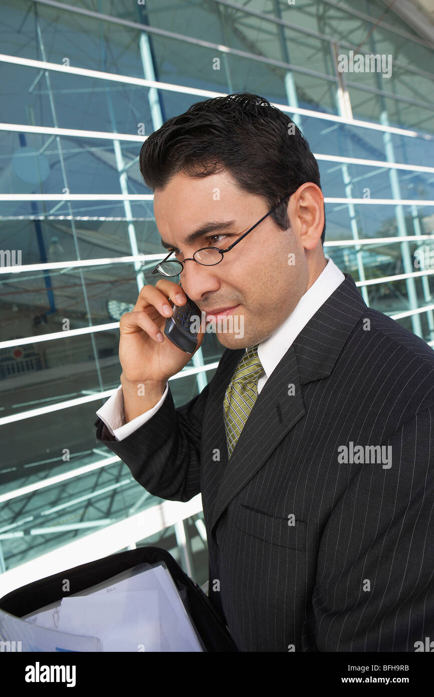Businessman using mobile phone outside office building Stock Photo - Alamy