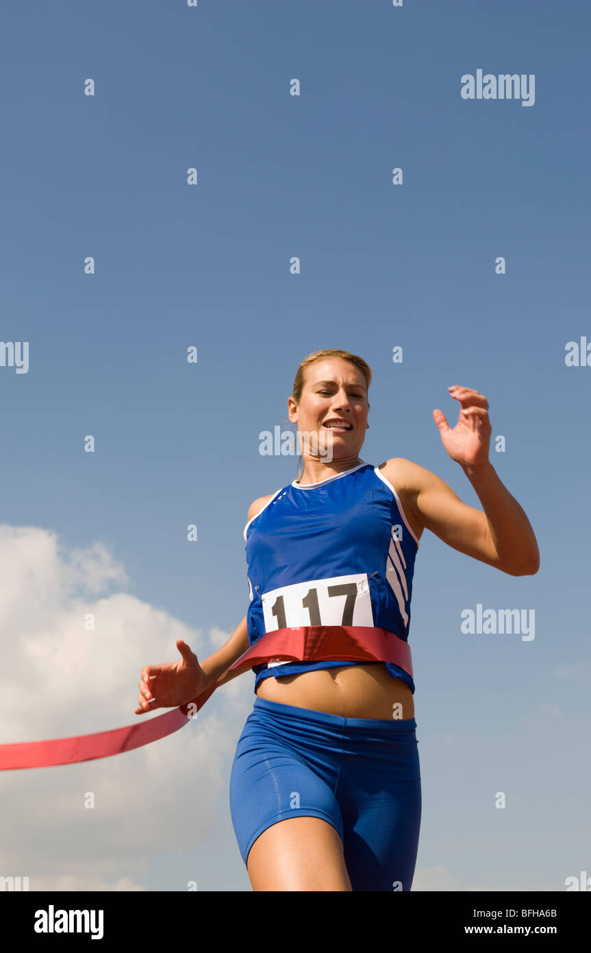 Female track athlete crossing finishing line Stock Photo - Alamy