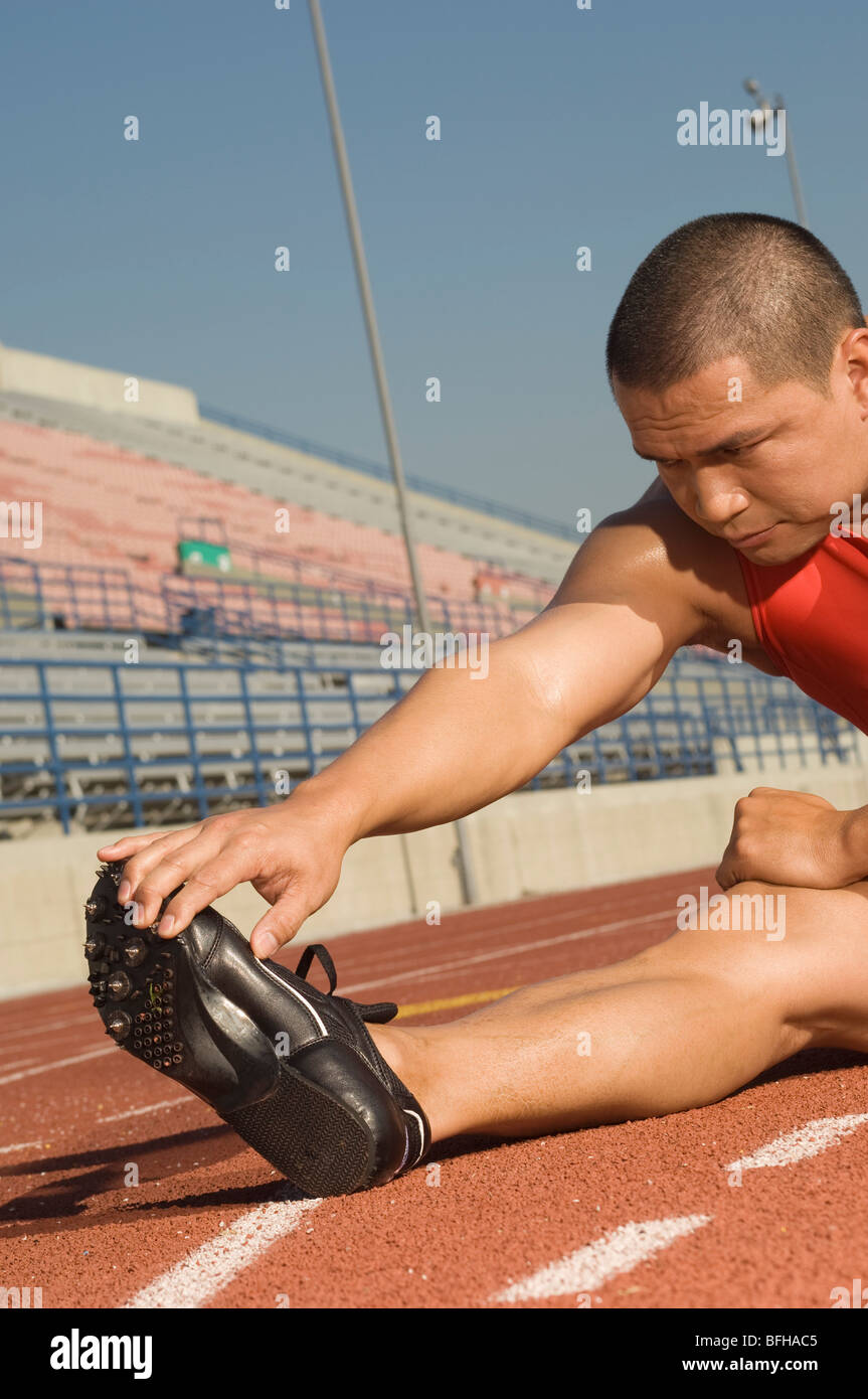 Male athlete stretching on track Stock Photo - Alamy