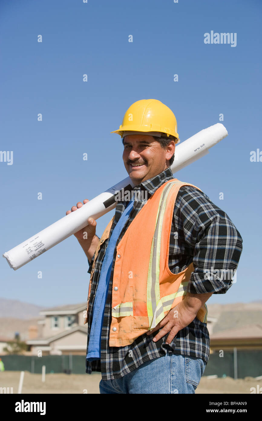 Construction worker holding building plans Stock Photo - Alamy