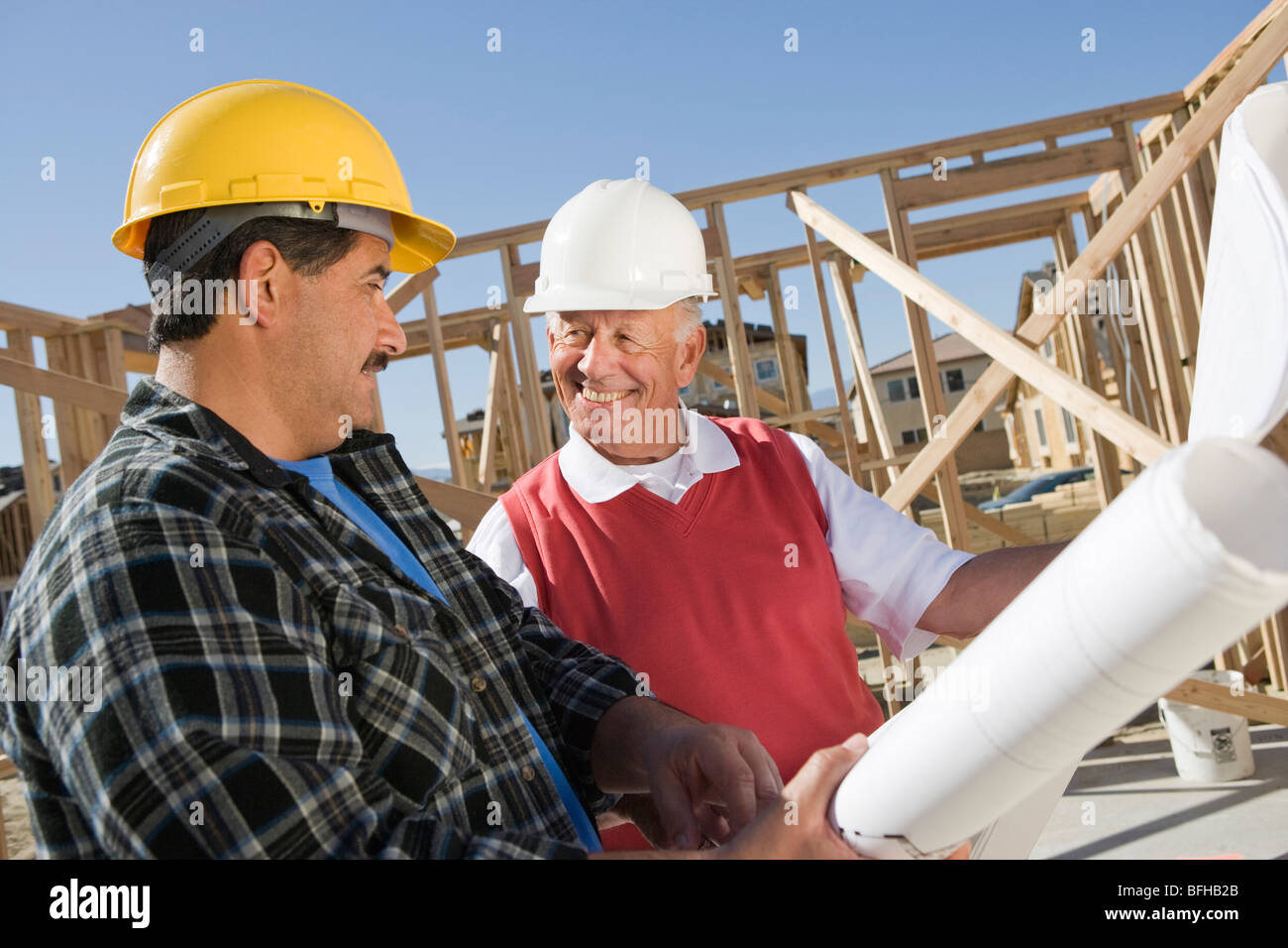 Construction workers observing plans on construction site Stock Photo ...