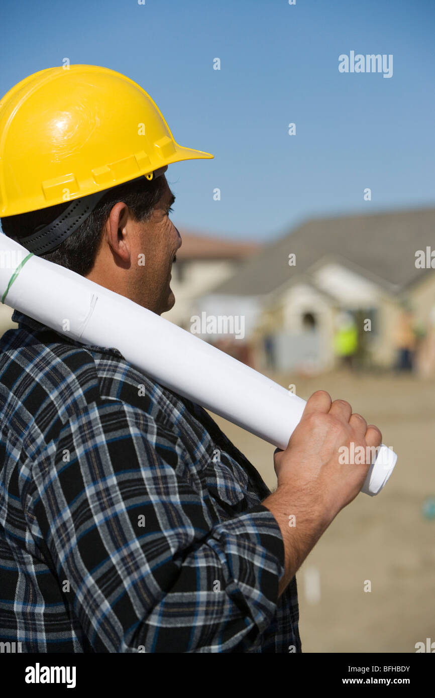 Construction worker holding rolled up blueprint Stock Photo - Alamy