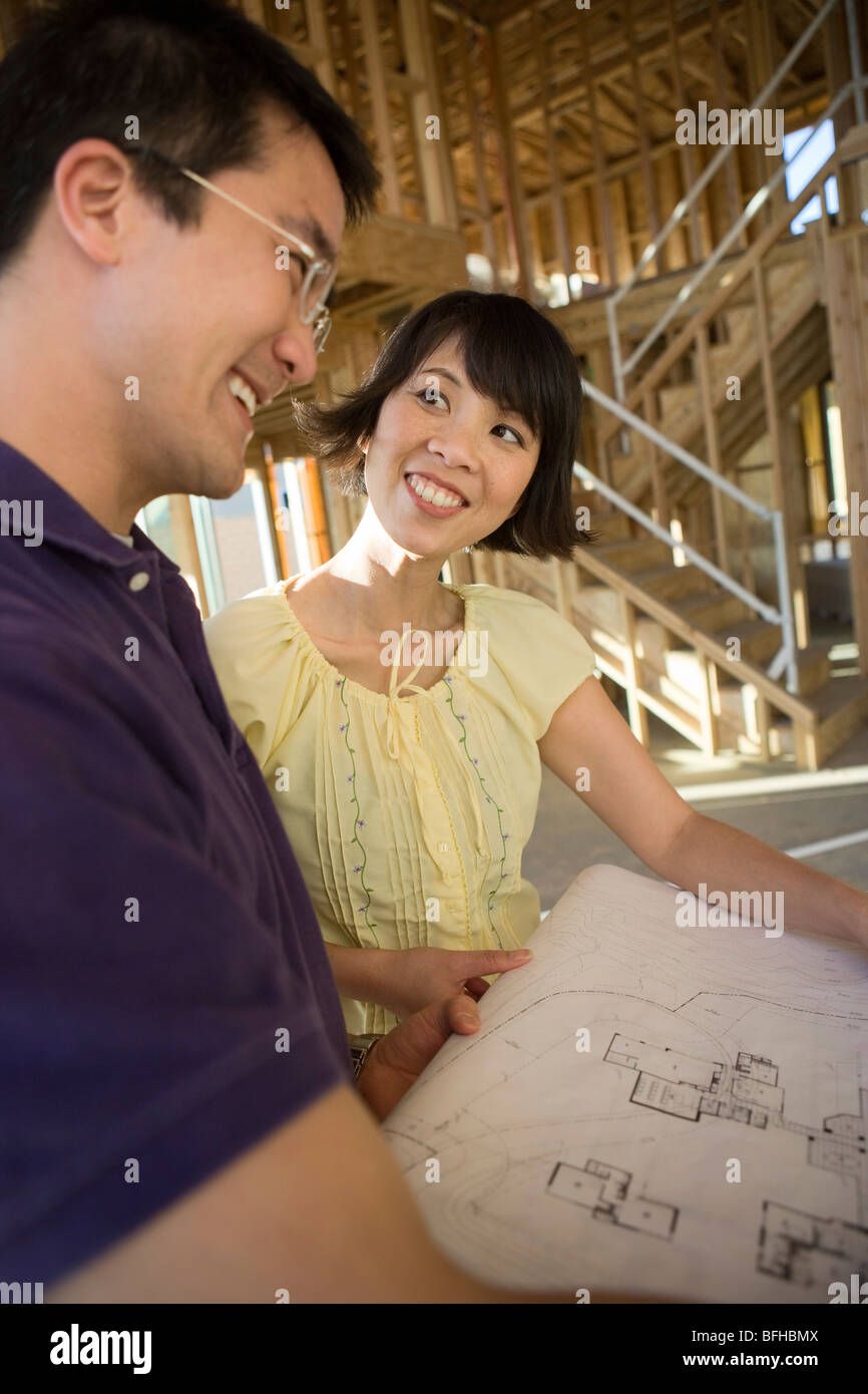 Couple over blueprint in construction site Stock Photo - Alamy