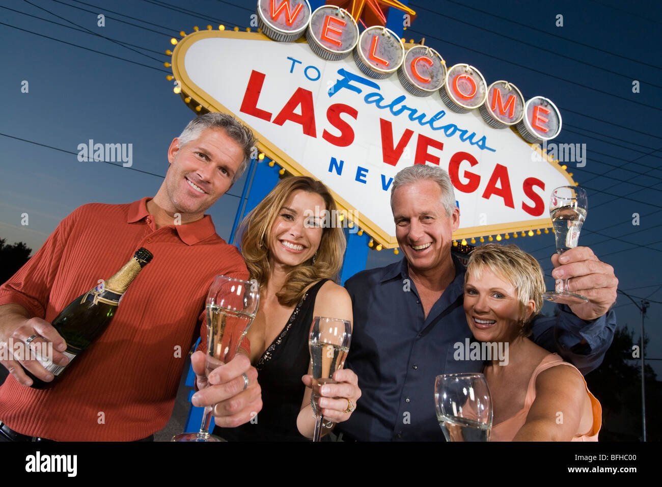 Two women and two men posing in front of Welcome to Las Vegas sign ...