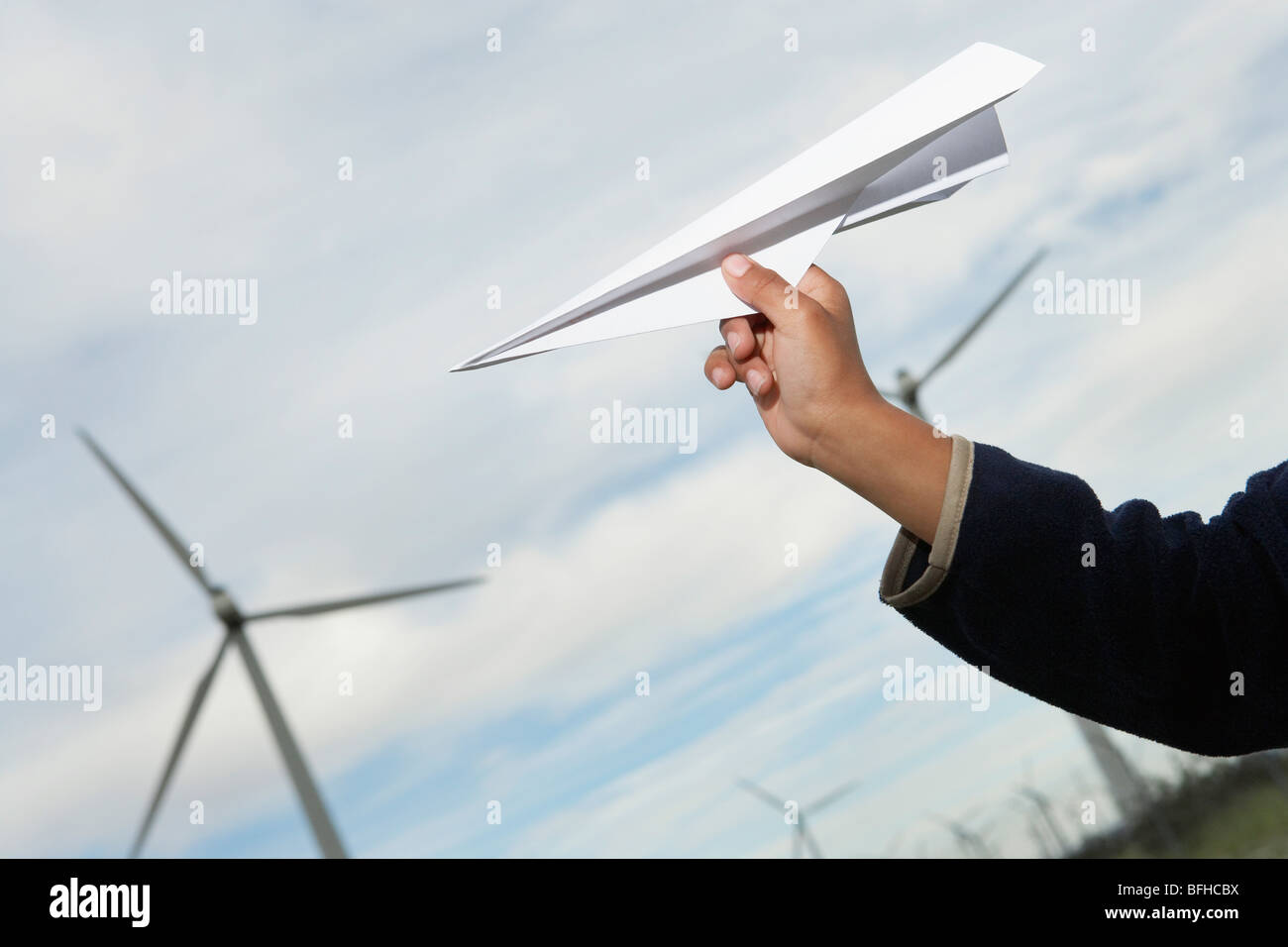 Boys hand throwing paper plane at wind farm, close-up Stock Photo - Alamy