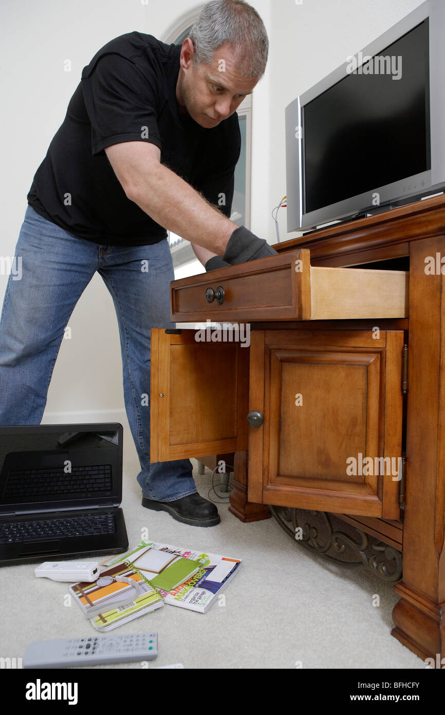 Burglar looking through drawers in house Stock Photo - Alamy