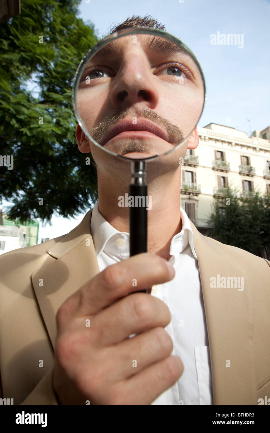 Man looking through magnifying glass Stock Photo - Alamy
