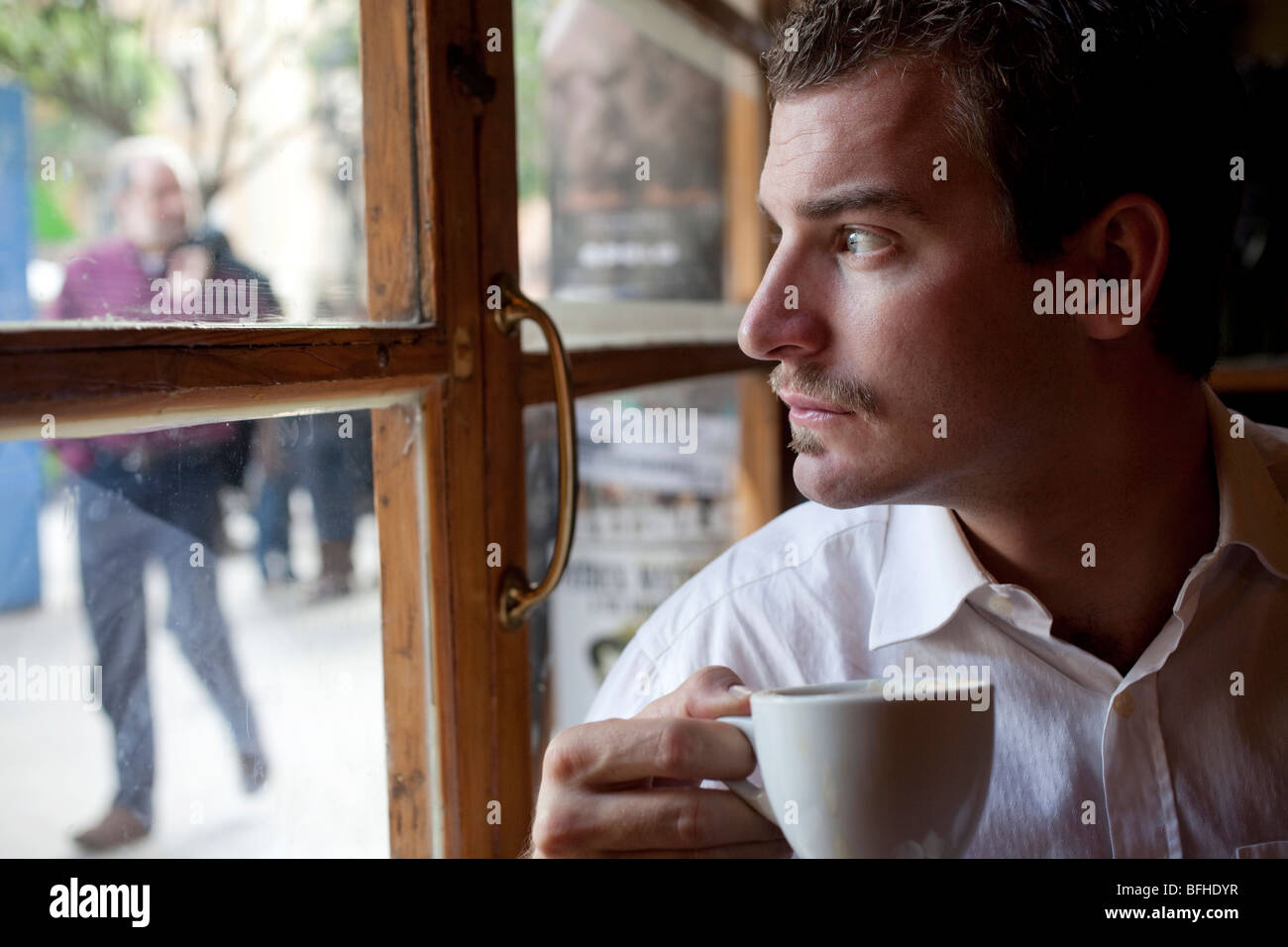 Young man looking out a window and drinking cafe Stock Photo - Alamy