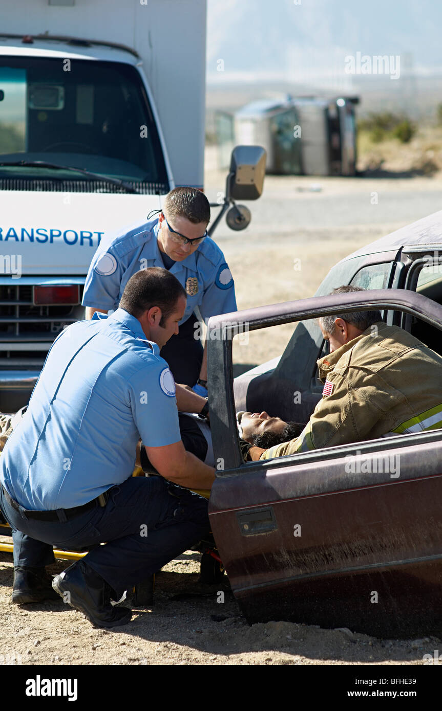 Firefighter and paramedics rescuing victim from crashed car Stock Photo ...