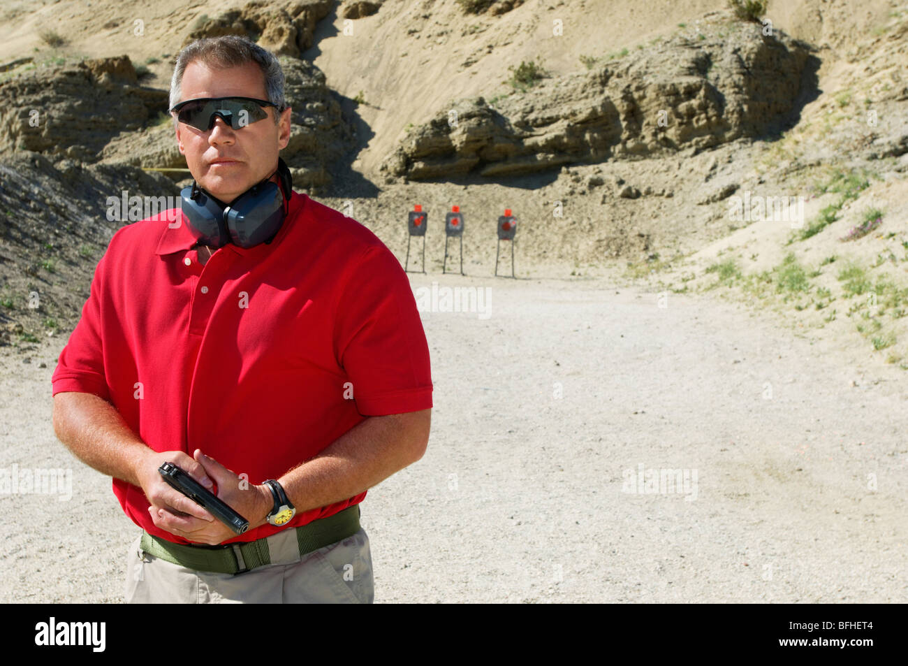 Man holding hand gun at firing range, portrait Stock Photo - Alamy