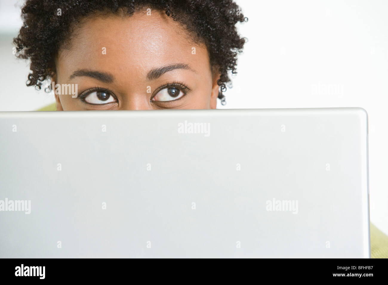 Mid-adult business woman peeking from behind laptop Stock Photo - Alamy