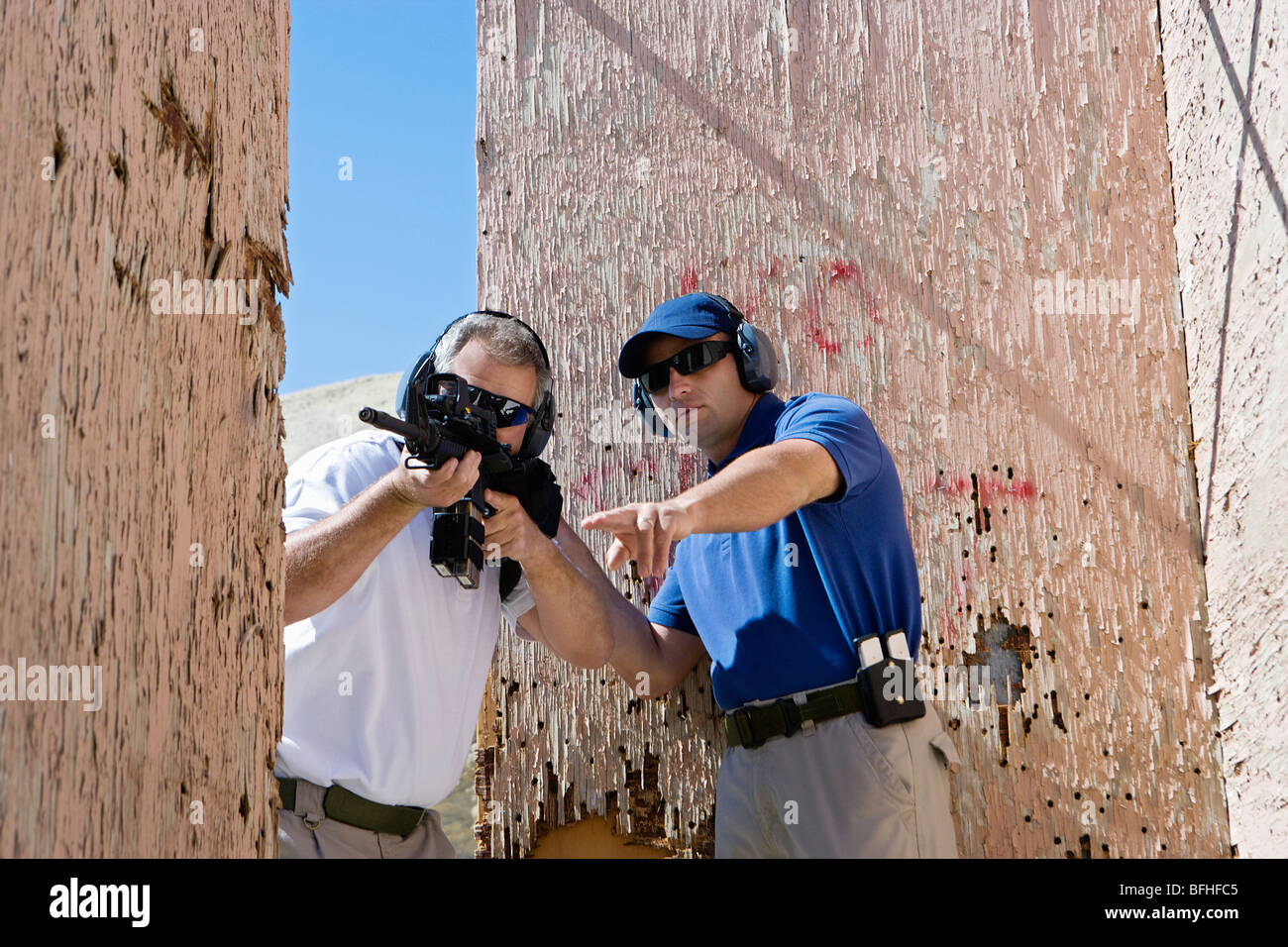 Instructor assisting man aiming machine gun at firing range Stock Photo ...