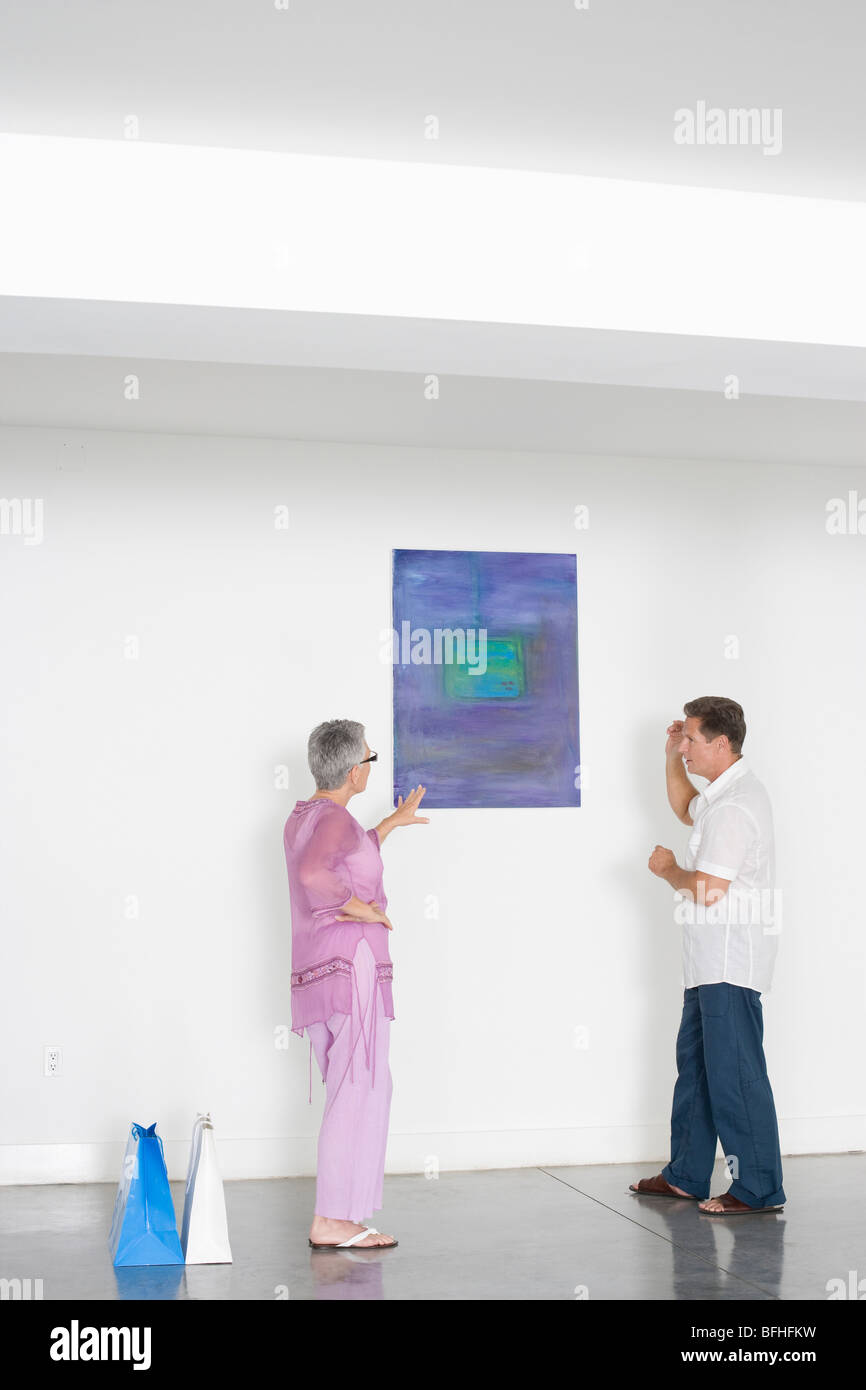 Couple contemplating paintings in gallery Stock Photo - Alamy