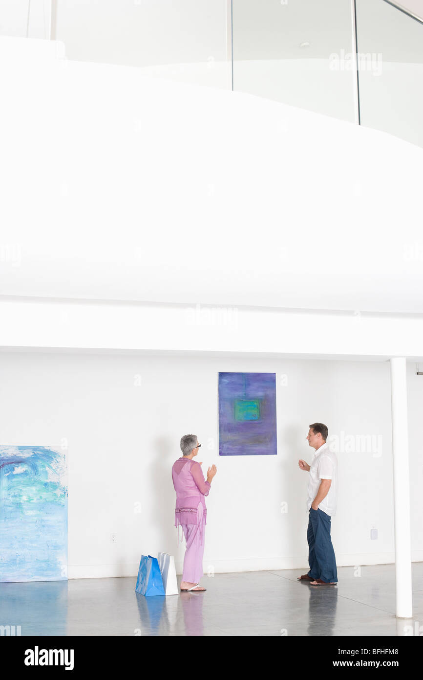 Couple contemplating paintings in gallery Stock Photo - Alamy