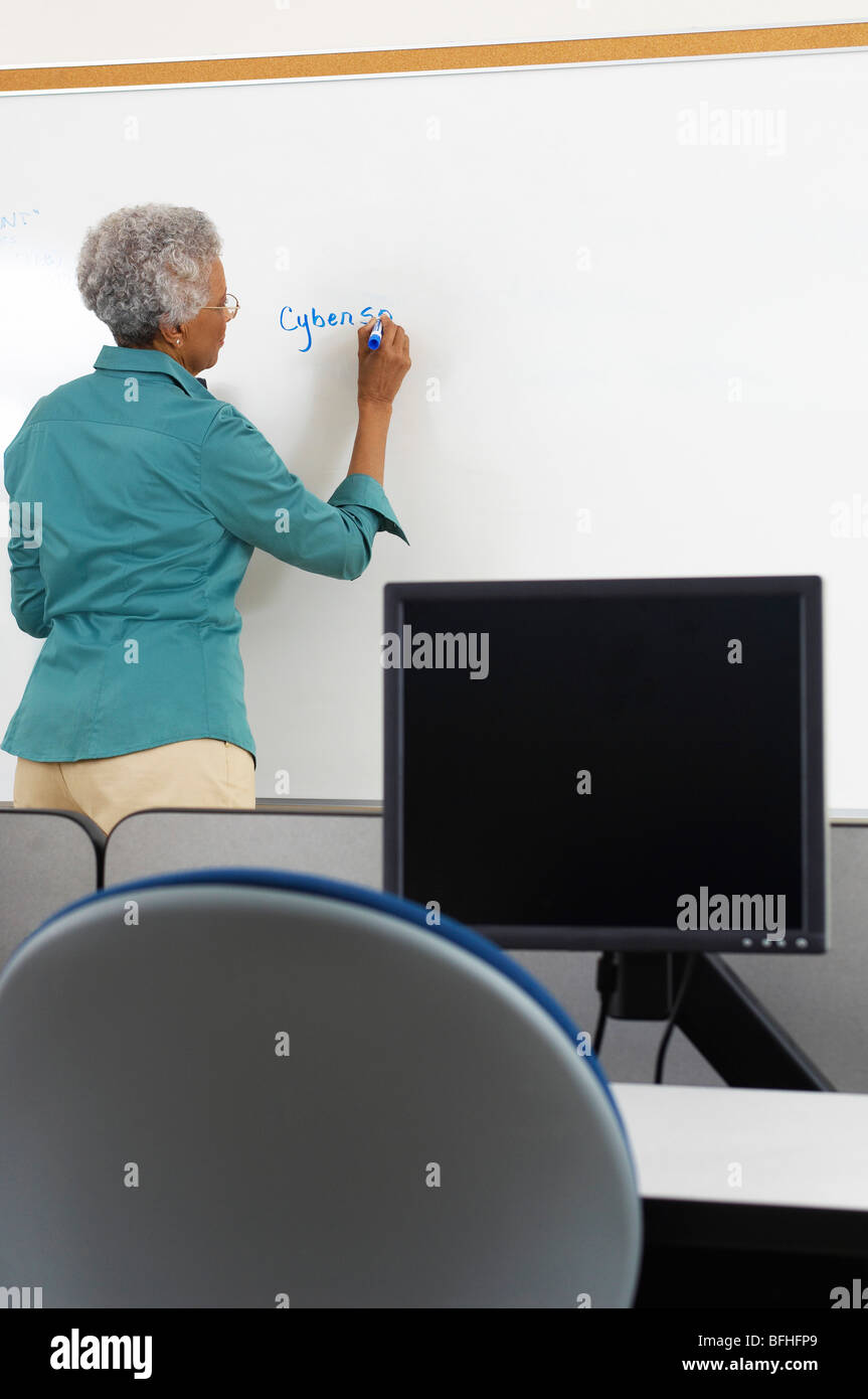 Female teacher writing on whiteboard in computer classroom Stock Photo ...