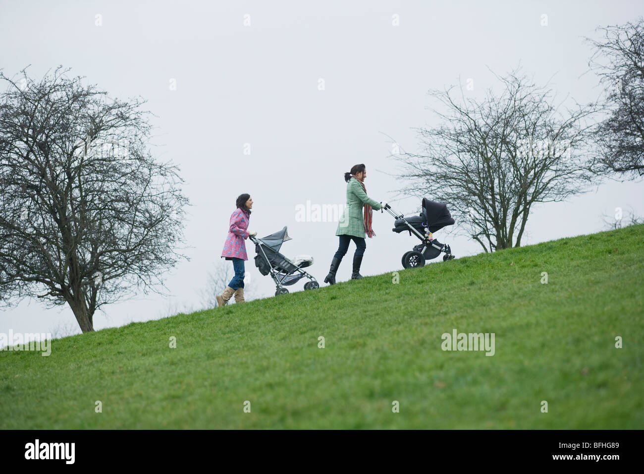 Two mothers pushing stroller uphill Stock Photo - Alamy