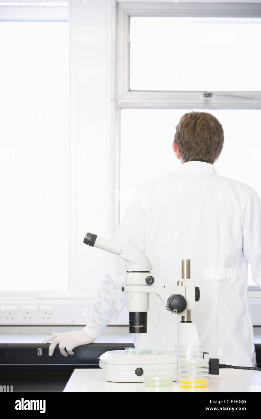 Scientist standing behind microscope in laboratory Stock Photo - Alamy