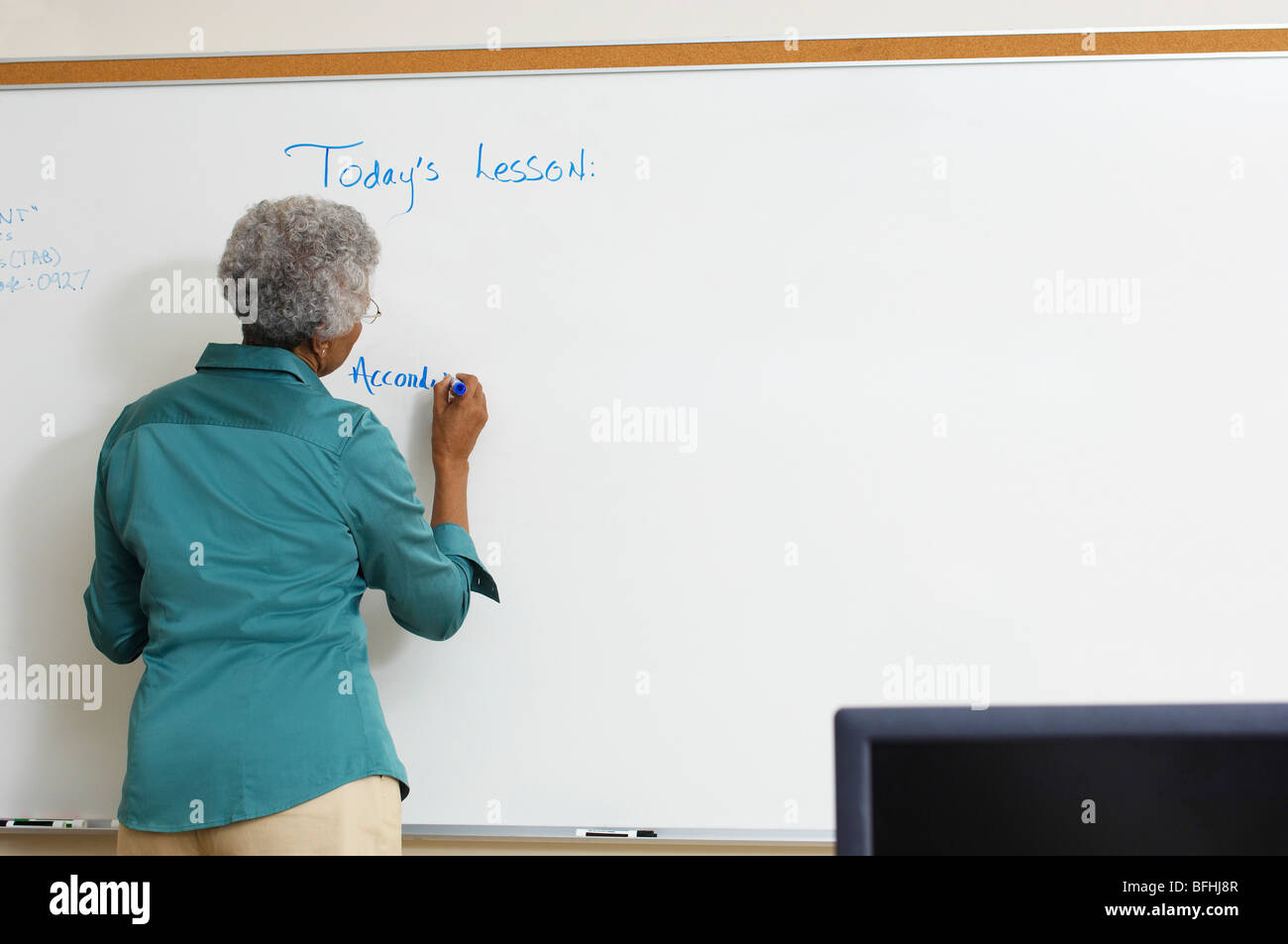 Female teacher writing on whiteboard in classroom Stock Photo - Alamy