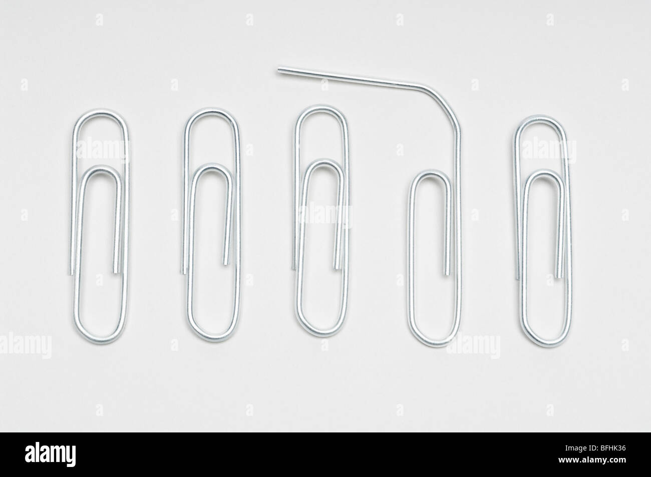 Row of paper clips with one bent Stock Photo - Alamy