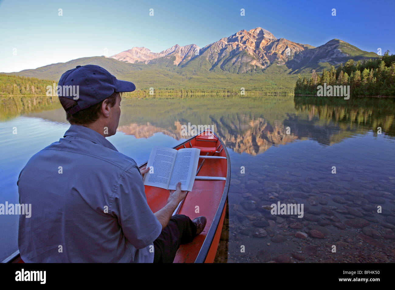 Middle age male reading book in canoe on mountain lake Stock Photo - Alamy