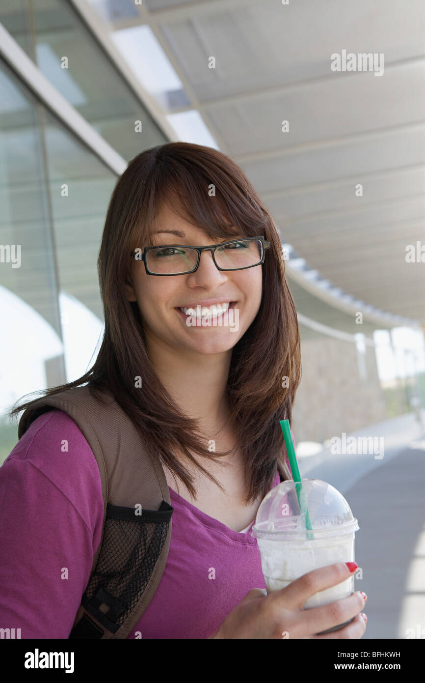 Female student holding drink at school, smiling, portrait Stock Photo ...