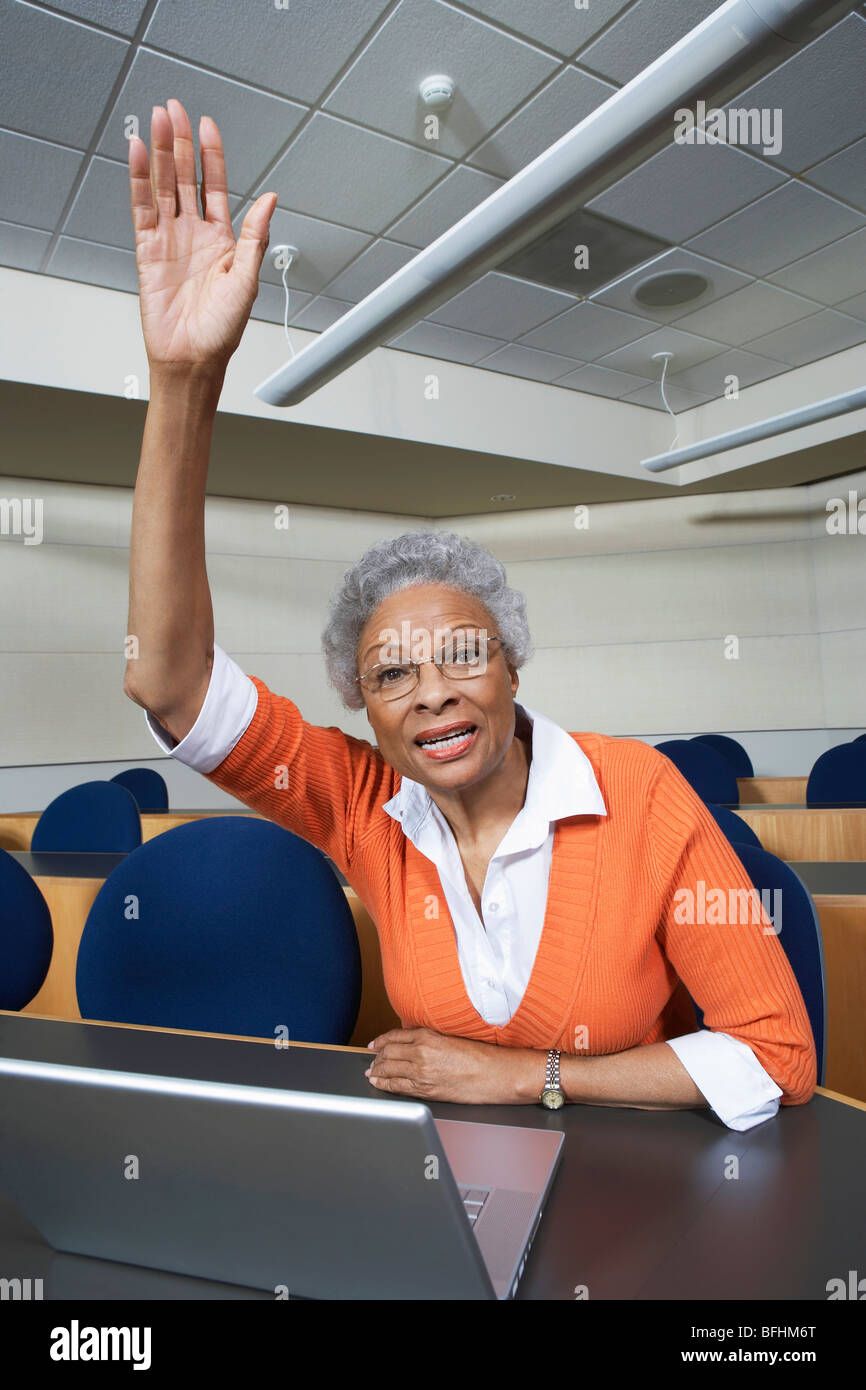 Mature female student raising hand in lecture theatre Stock Photo - Alamy