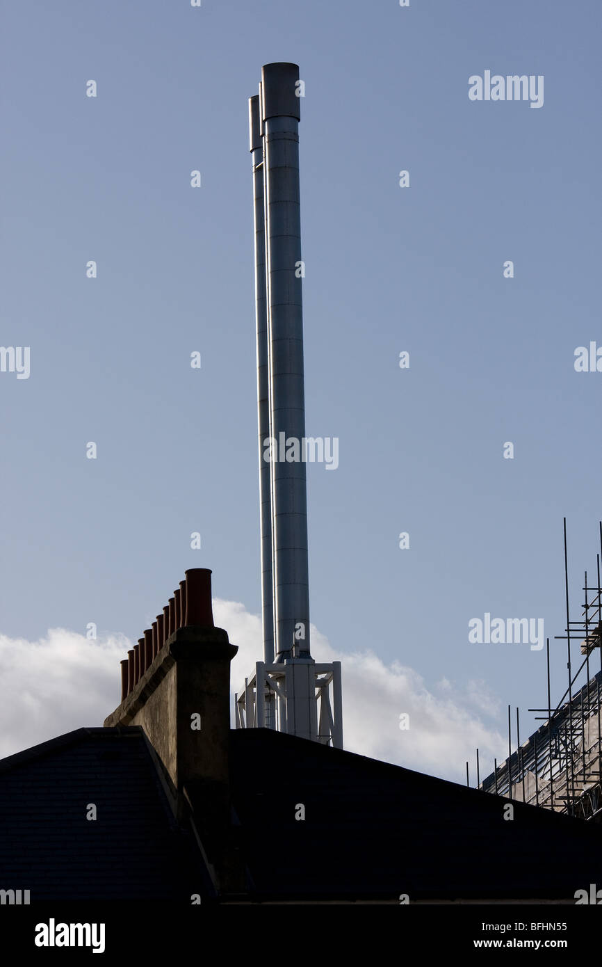 Industrial chimneys tower over chimney pots in a residential street ...