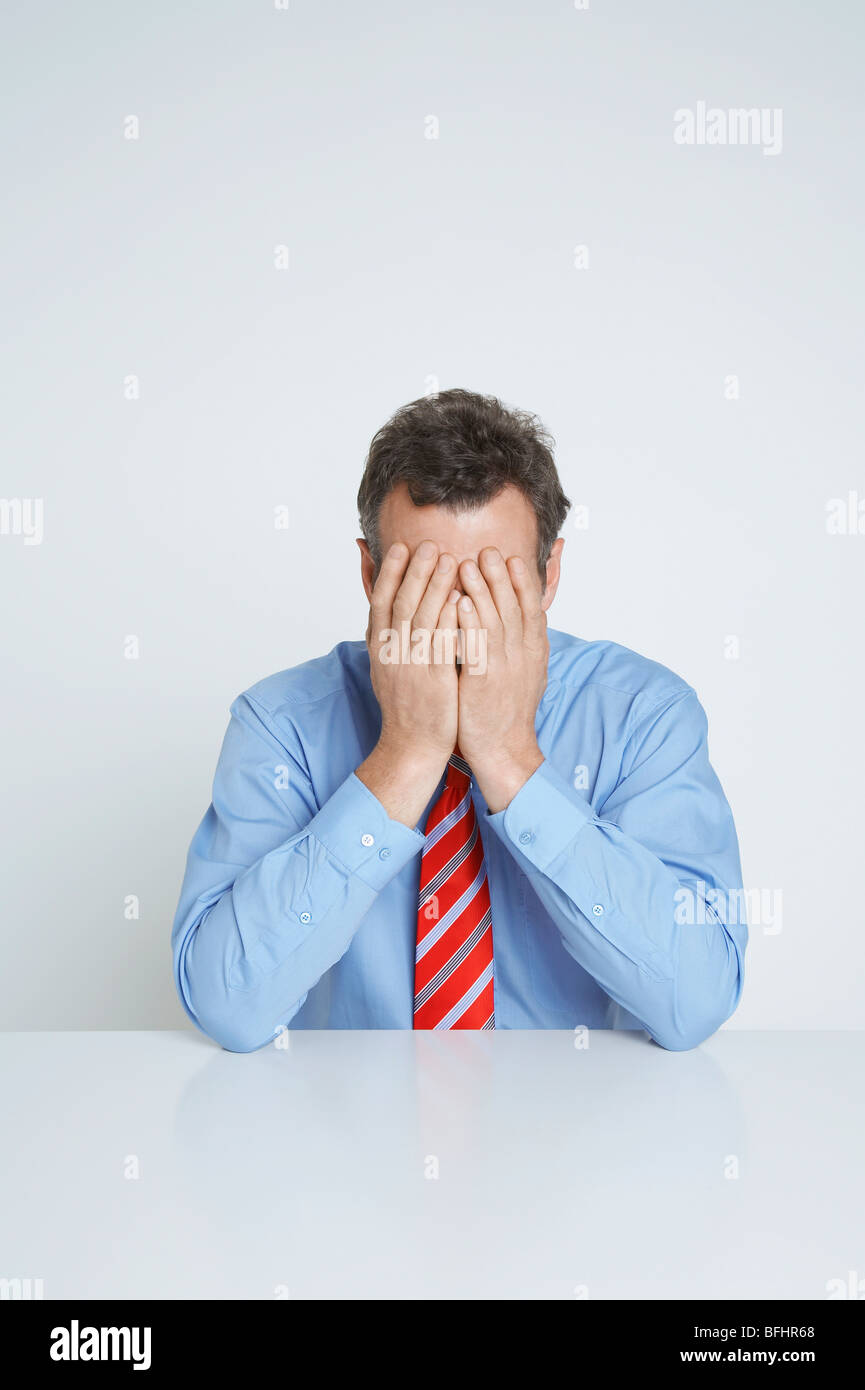 Studio shot of businessman with head in hands Stock Photo - Alamy