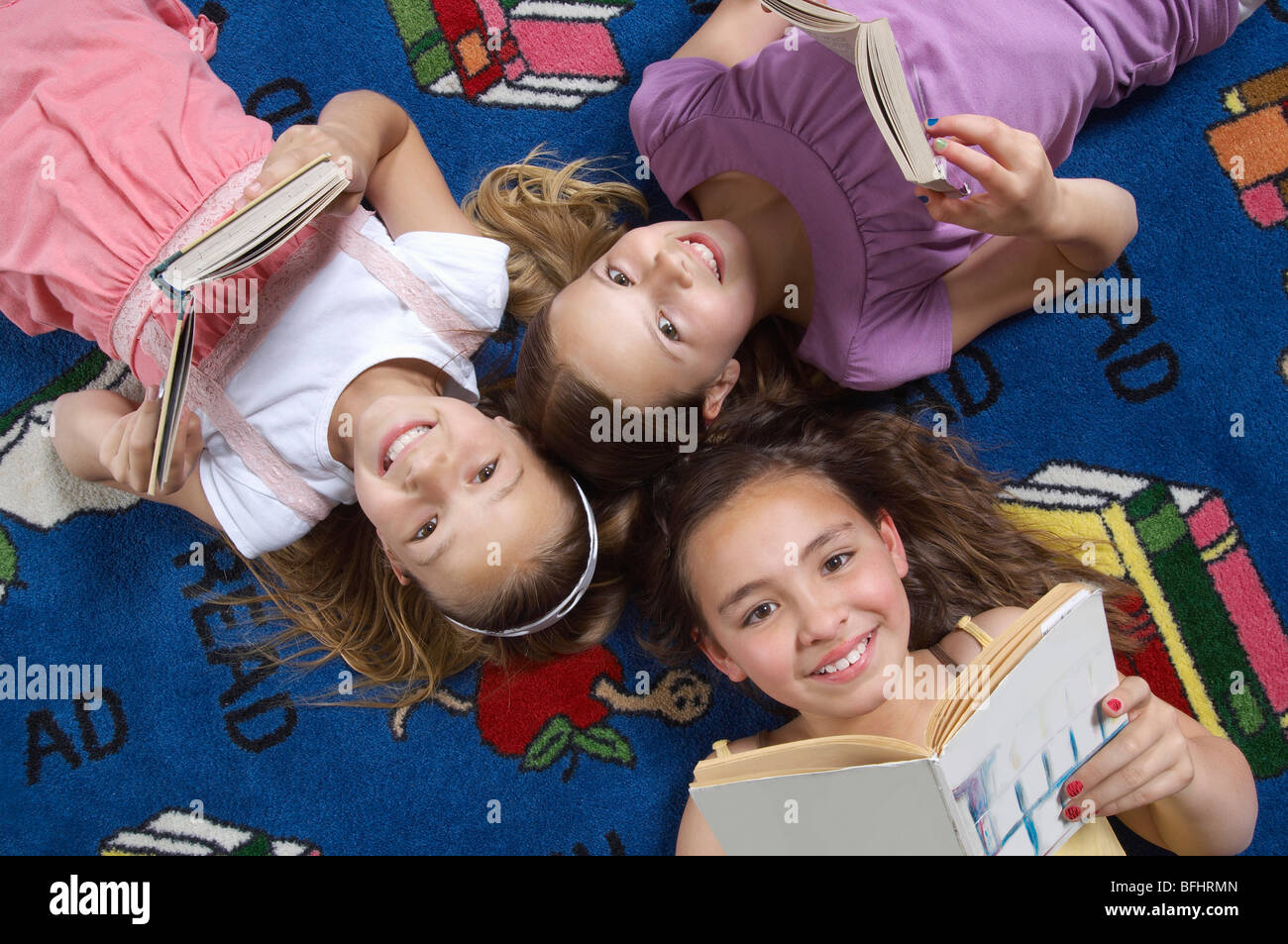 School girls reading books on floor in library Stock Photo - Alamy