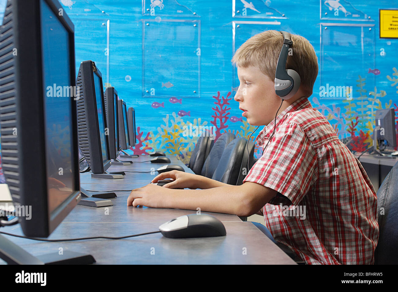 School boy wearing headphones in computer room Stock Photo - Alamy