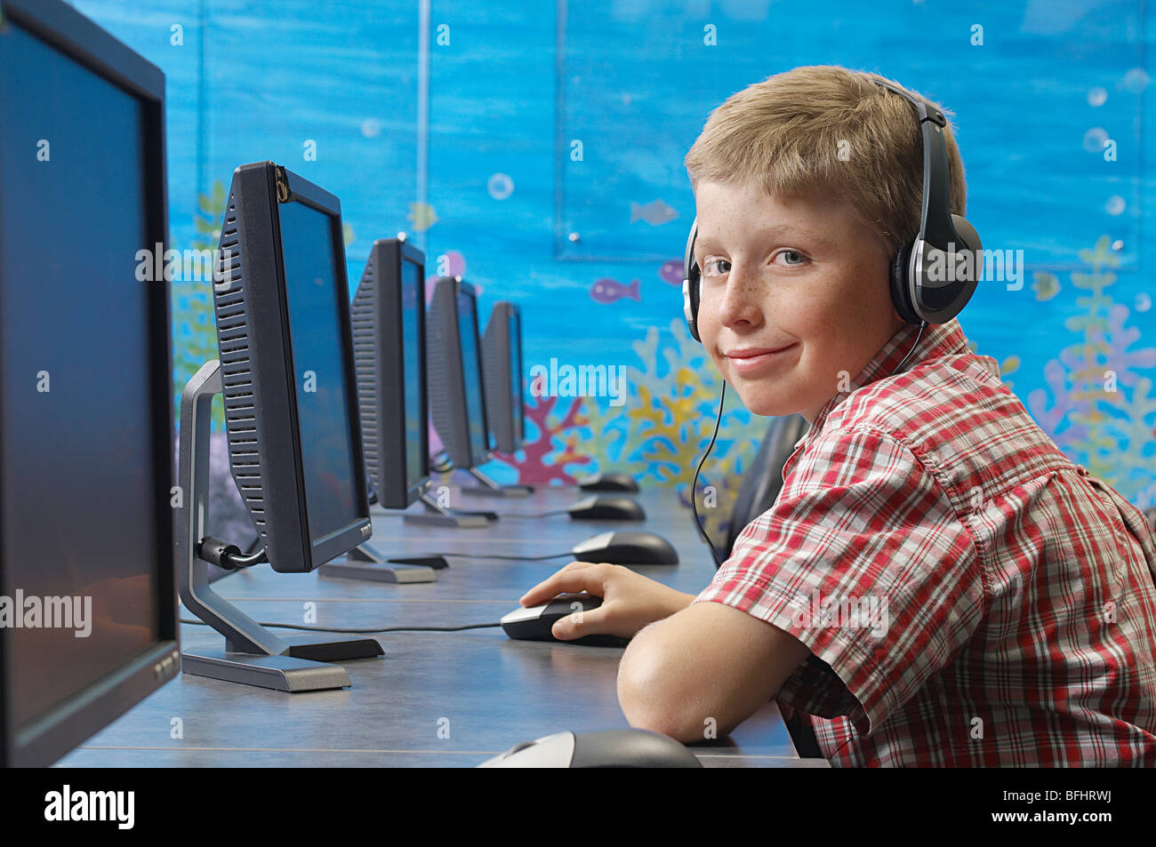 School boy wearing headphones in computer room, portrait Stock Photo ...