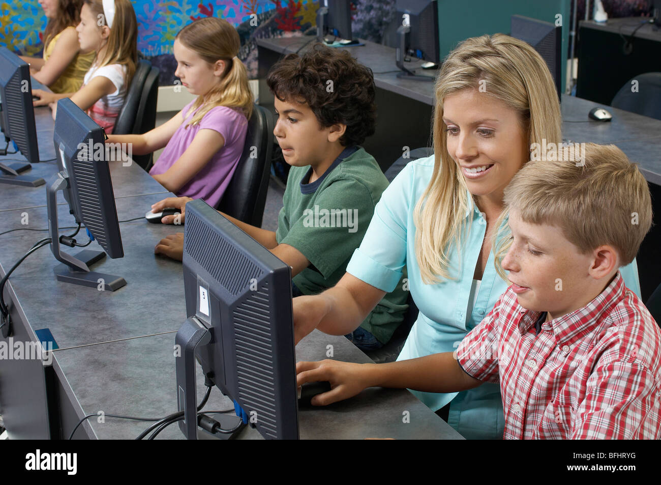 School children using computers with teacher in classroom Stock Photo ...