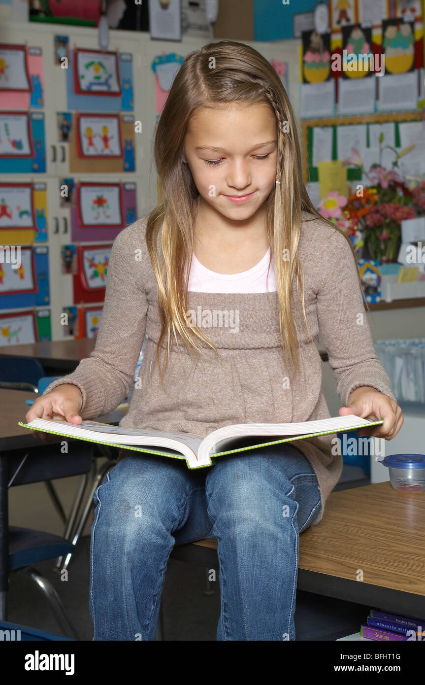 School girl reading book on desk in classroom Stock Photo - Alamy