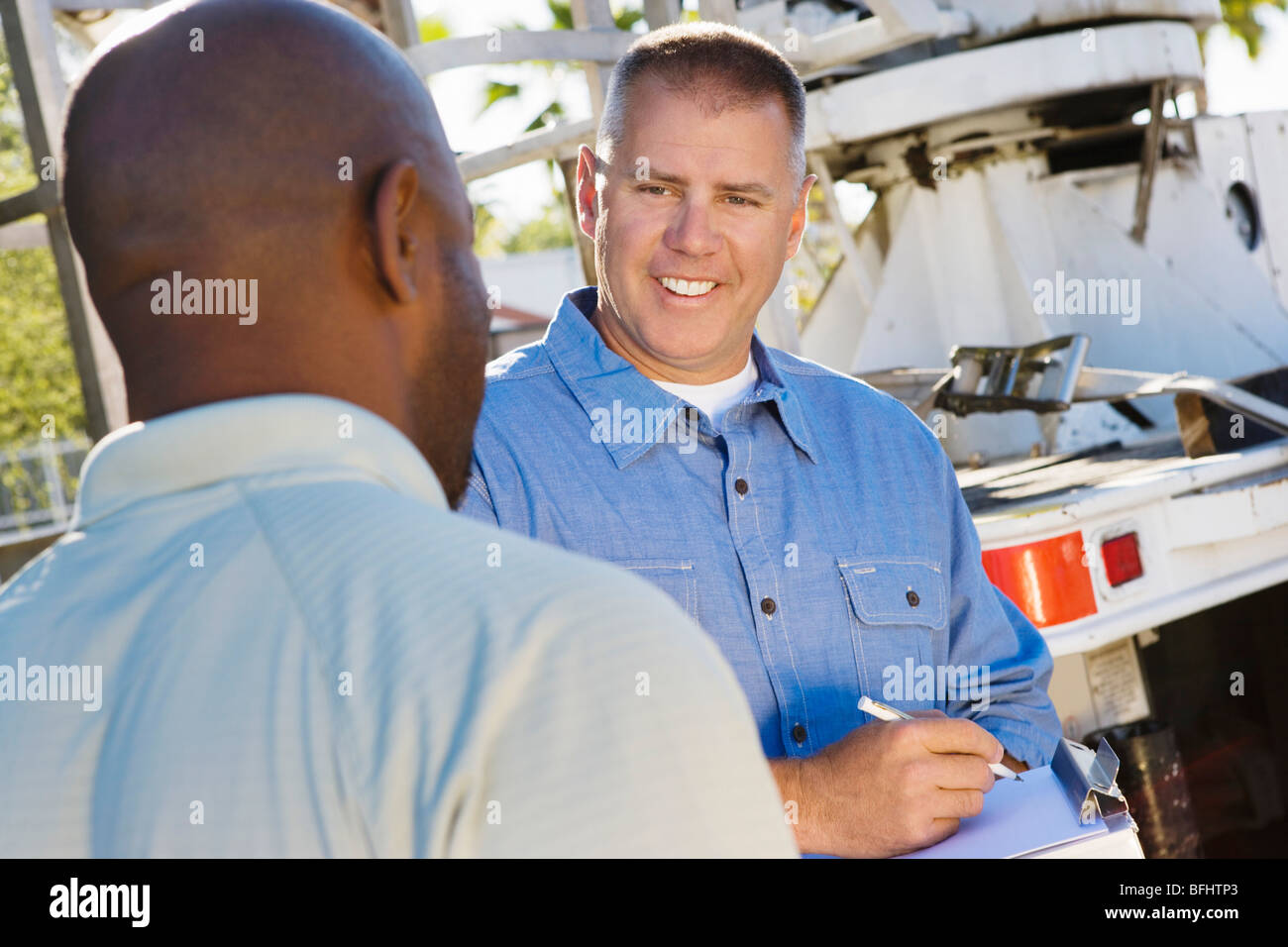 Mid-adult mechanic talking to co-worker Stock Photo - Alamy