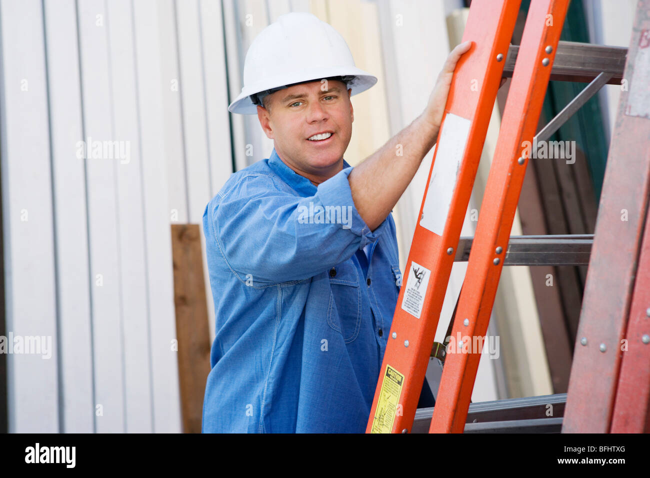Workman Standing by a Ladder Stock Photo - Alamy