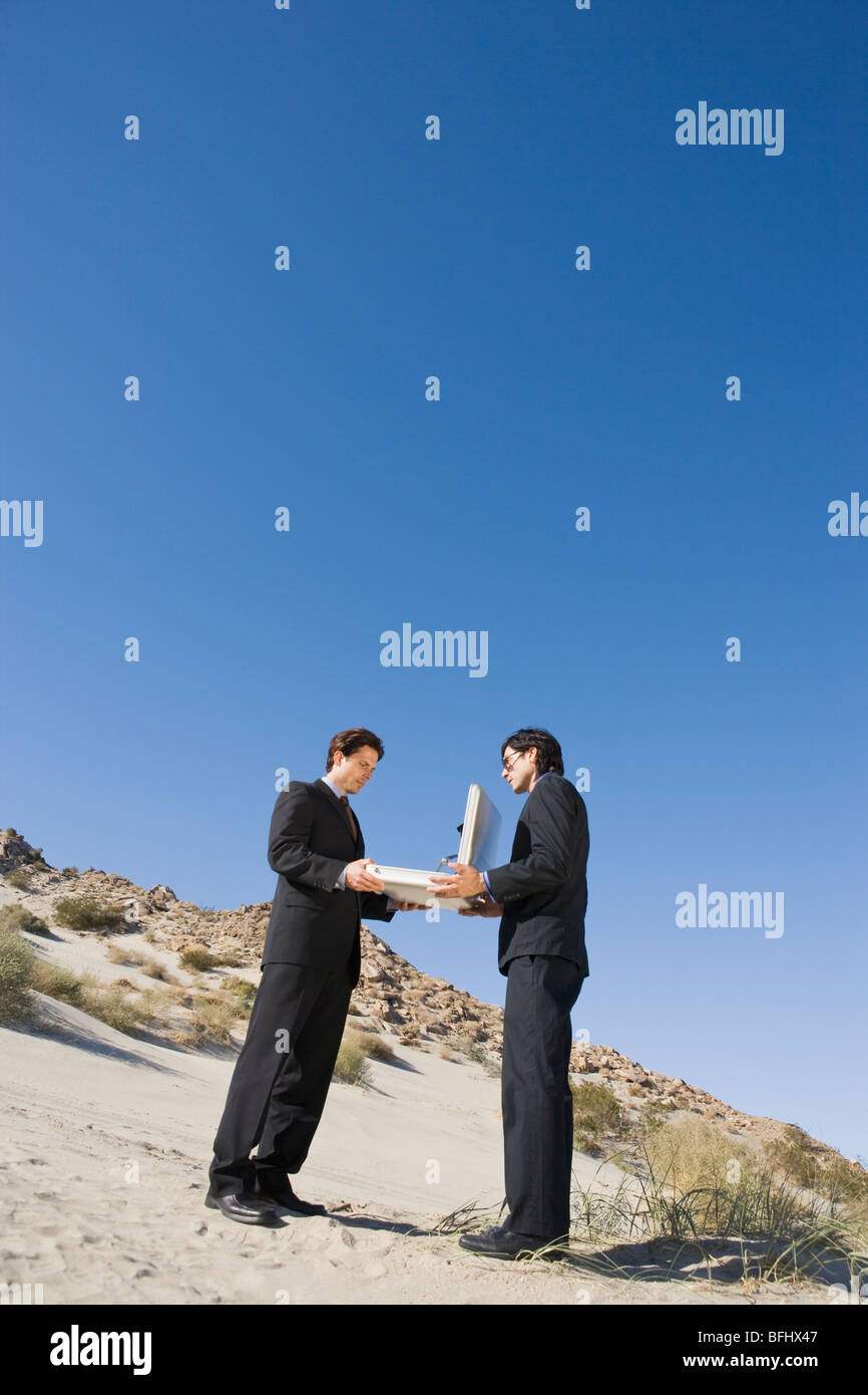 Two Businessmen Holding Open Briefcase in the Desert Stock Photo - Alamy