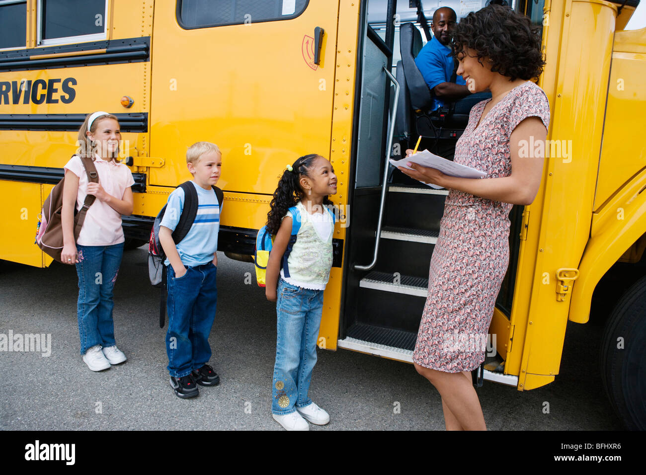Teacher Loading Elementary Students on School Bus Stock Photo - Alamy
