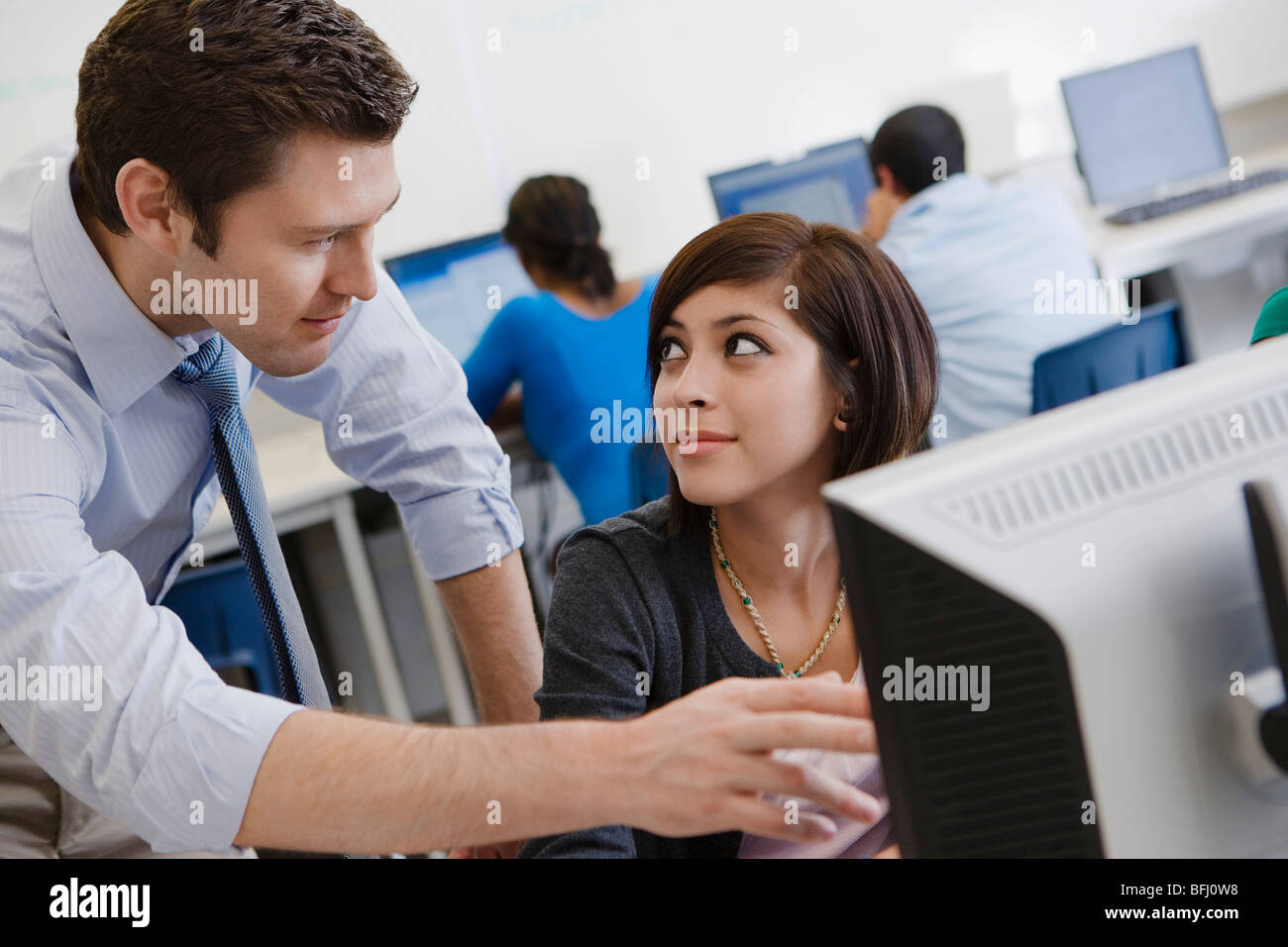 Teacher Helping Student in Computer Lab Stock Photo - Alamy