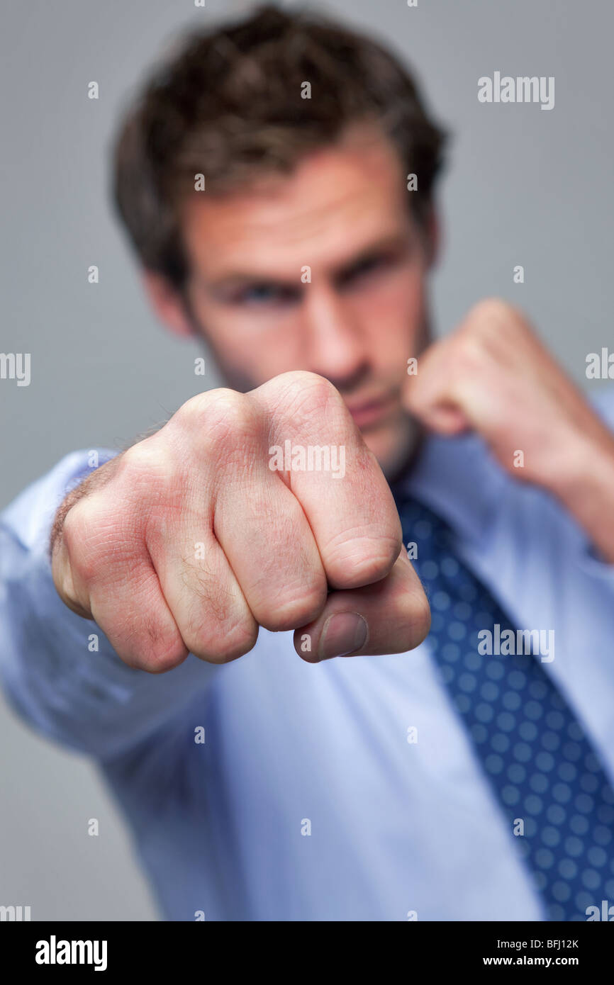 Businessman throwing a punch towards the camera, focus on his fist ...