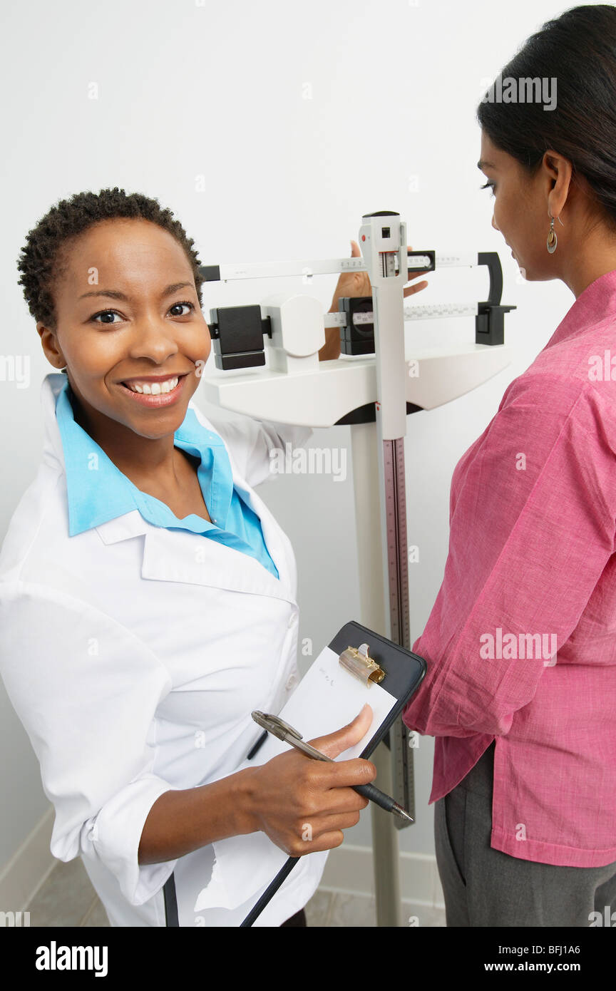 Female doctor weighing patient Stock Photo - Alamy
