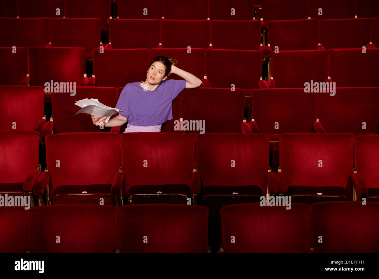 Young woman sitting in theatre stalls Stock Photo - Alamy