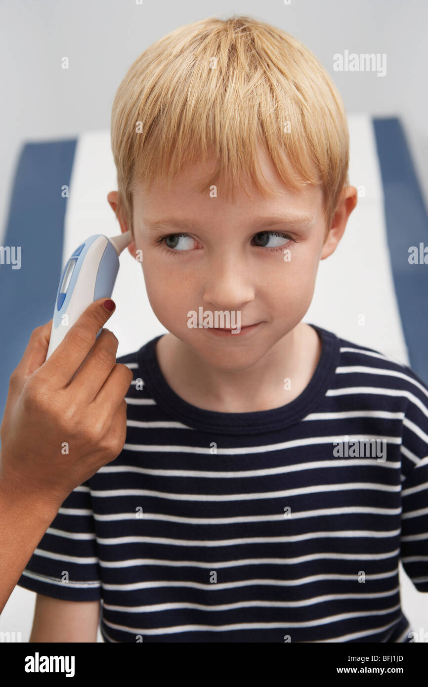 Boy having temperature taken with ear thermometer Stock Photo - Alamy