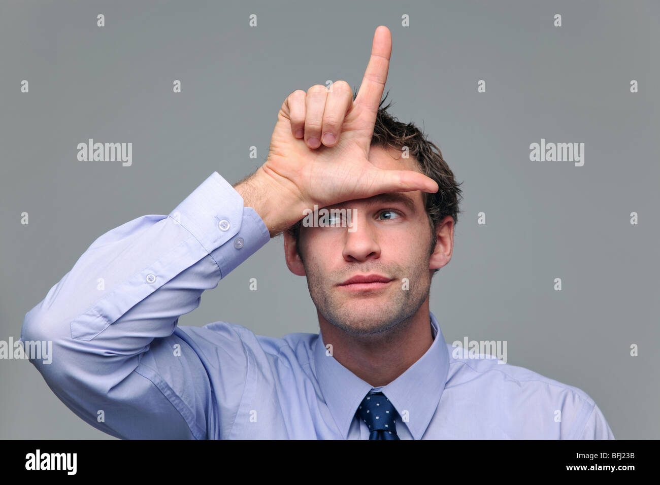 Businessman making a loser gesture with his hand Stock Photo - Alamy
